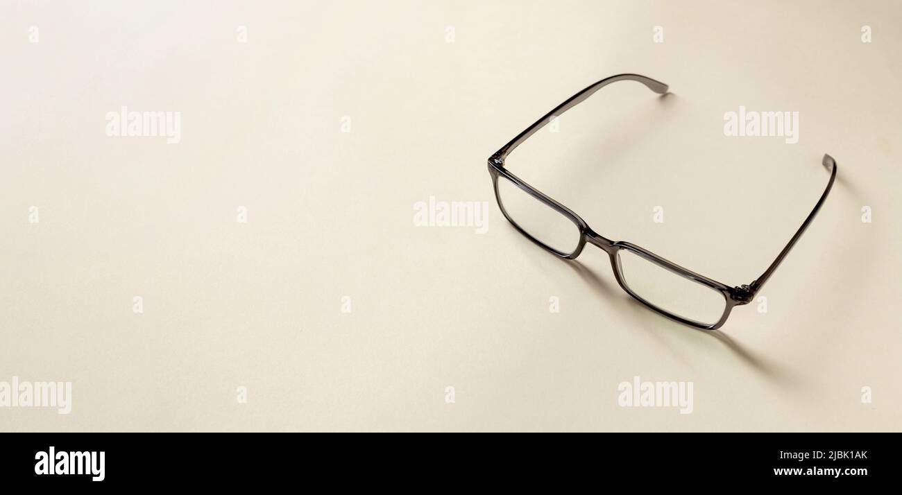 Top view of reading glasses on a cream color table. Empty space for ...