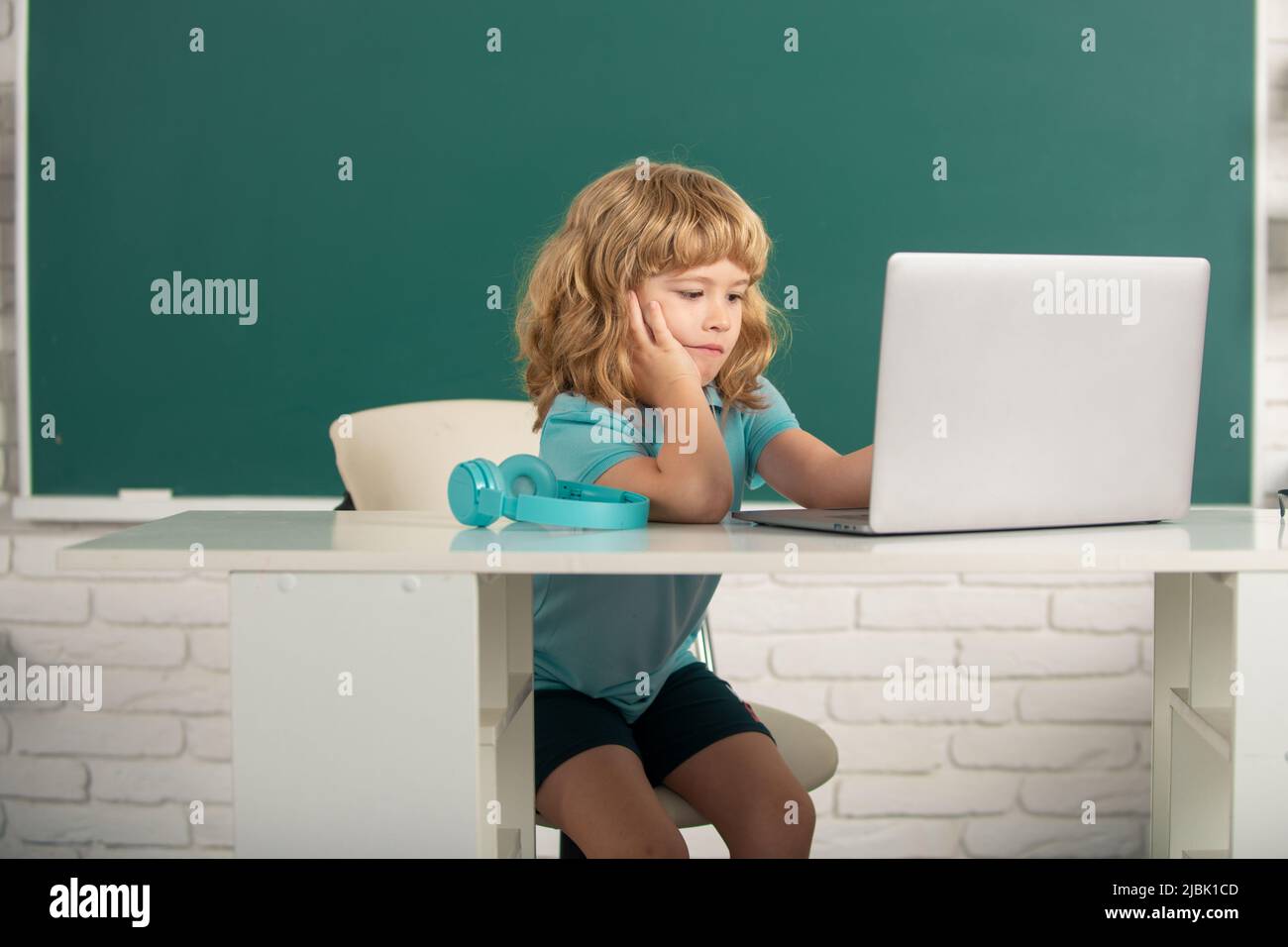 Kid boy learning lesson at school, making homework and using notebook ...