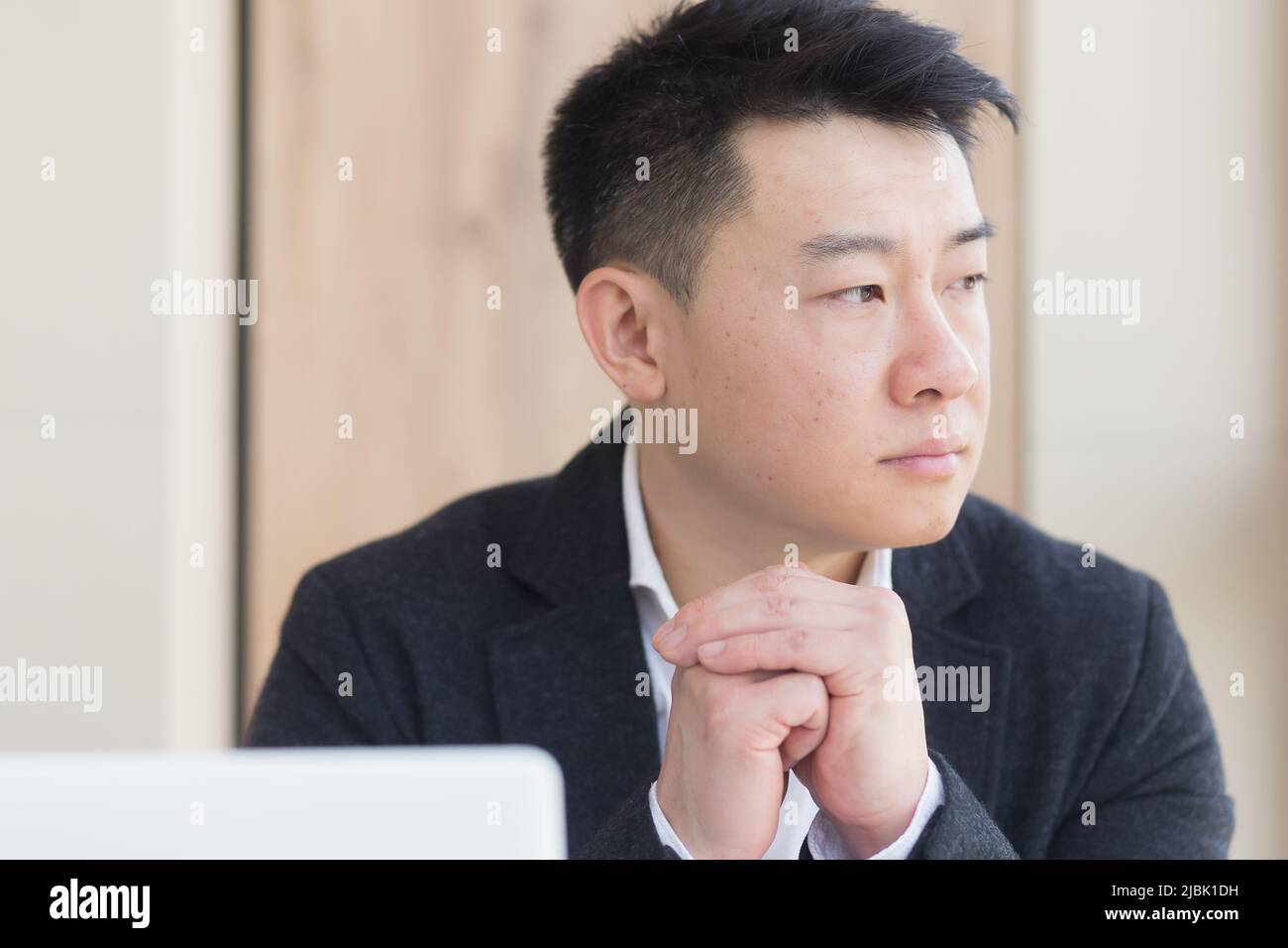 close-up portrait asian pensive young office worker man at workplace ...