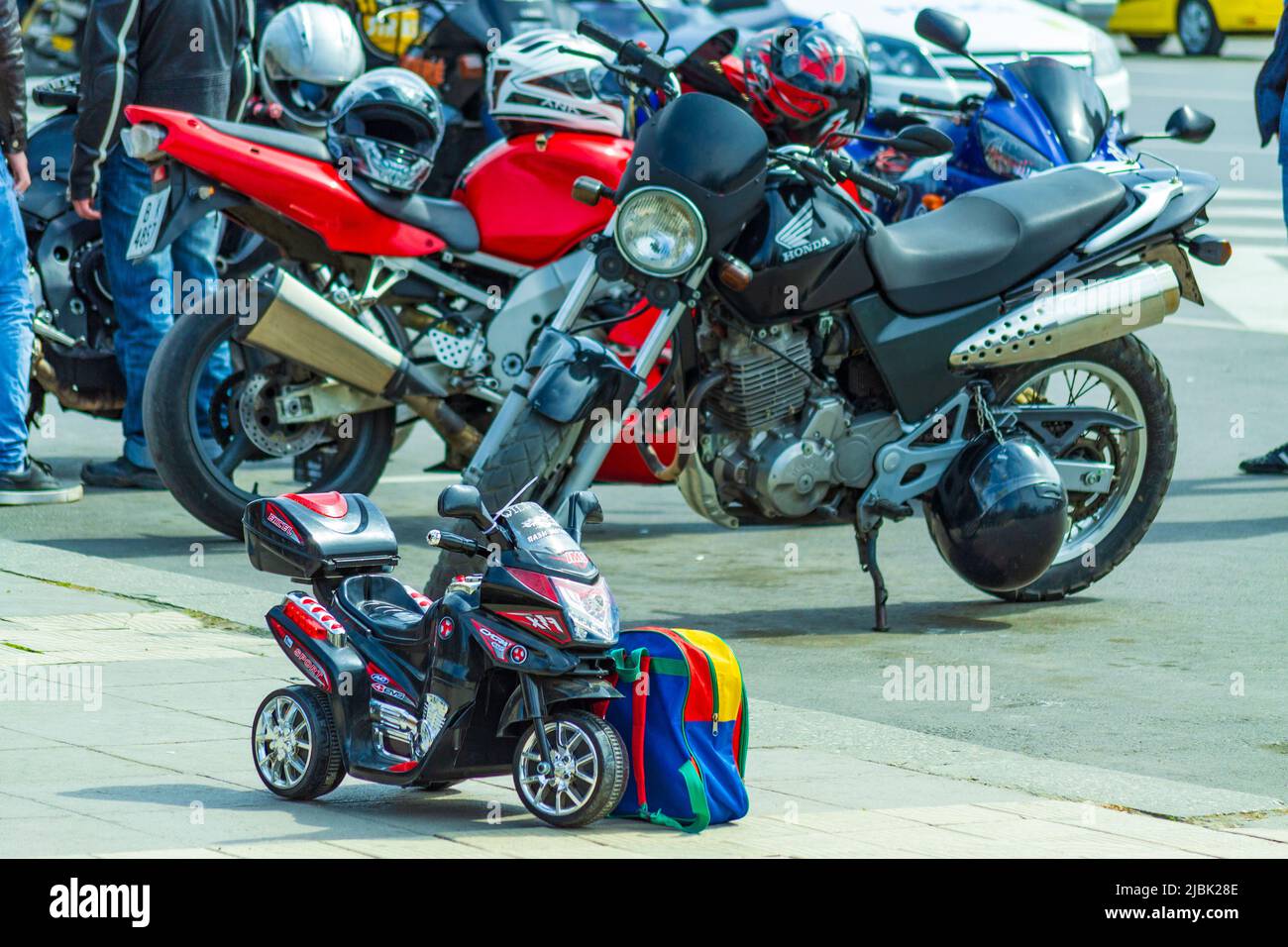 Children's motorcycle on the pavement by parked big motorcycles during ...