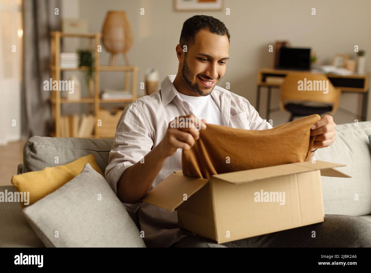 Satisfied African American male client taking out new clothes from ...