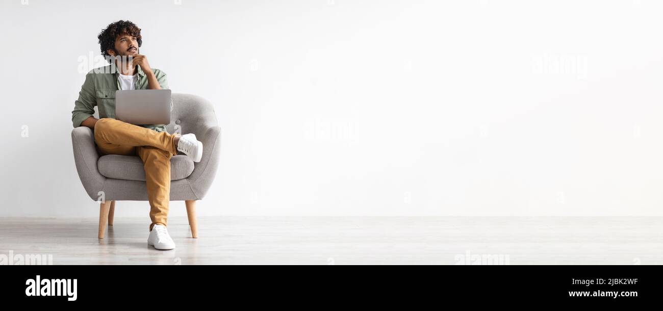 Pensive indian guy with computer on lap over white background Stock ...