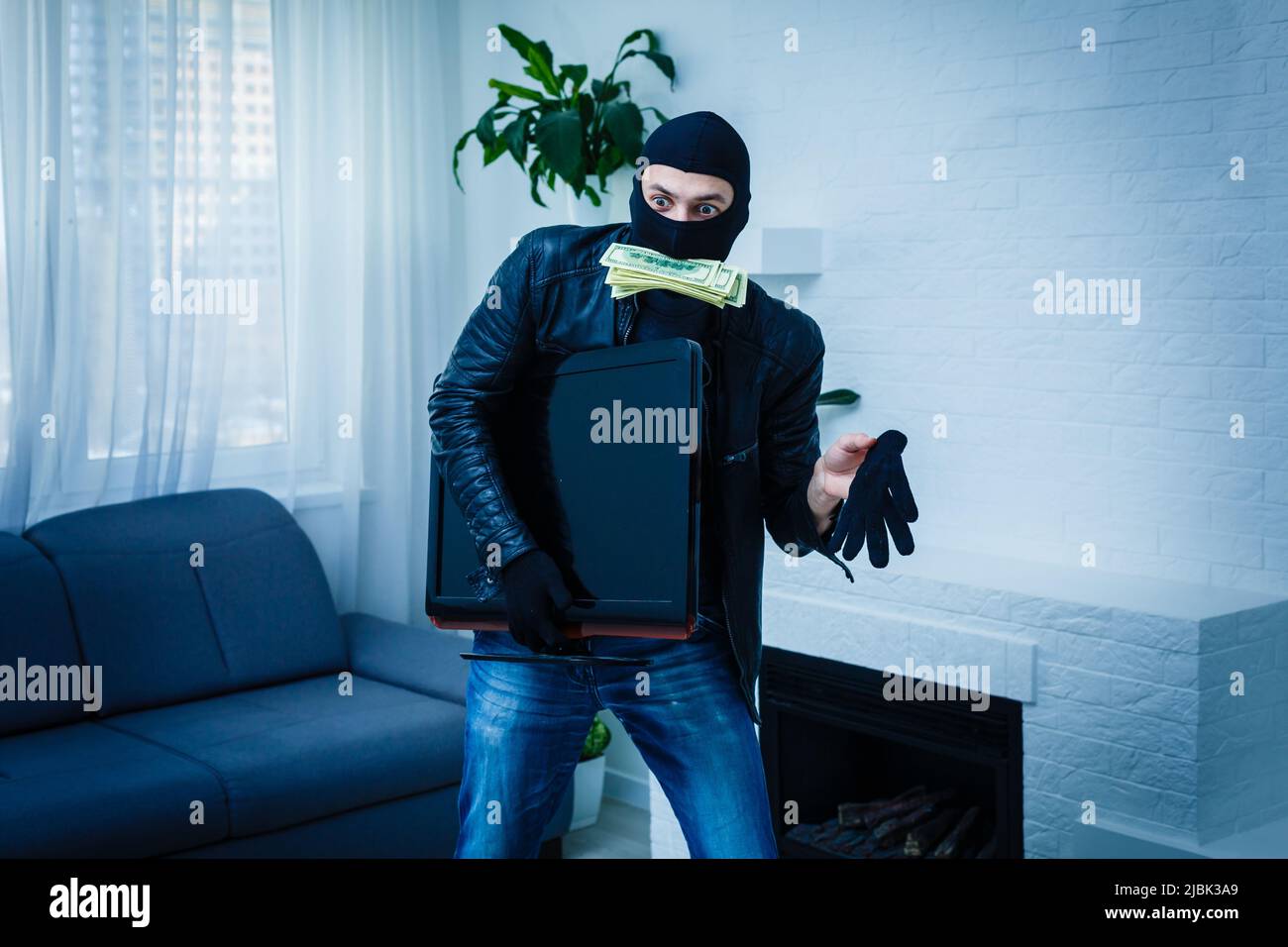 Robber man dressed in black hoodie stands with disguised face and holds ...