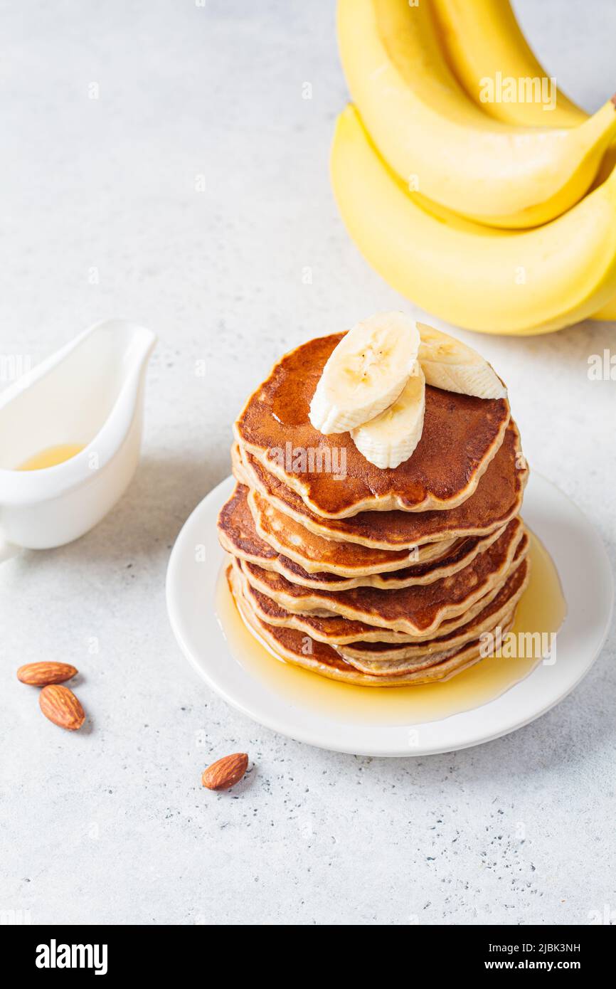 Stack of banana pancakes with syrup on a white plate, gray background ...