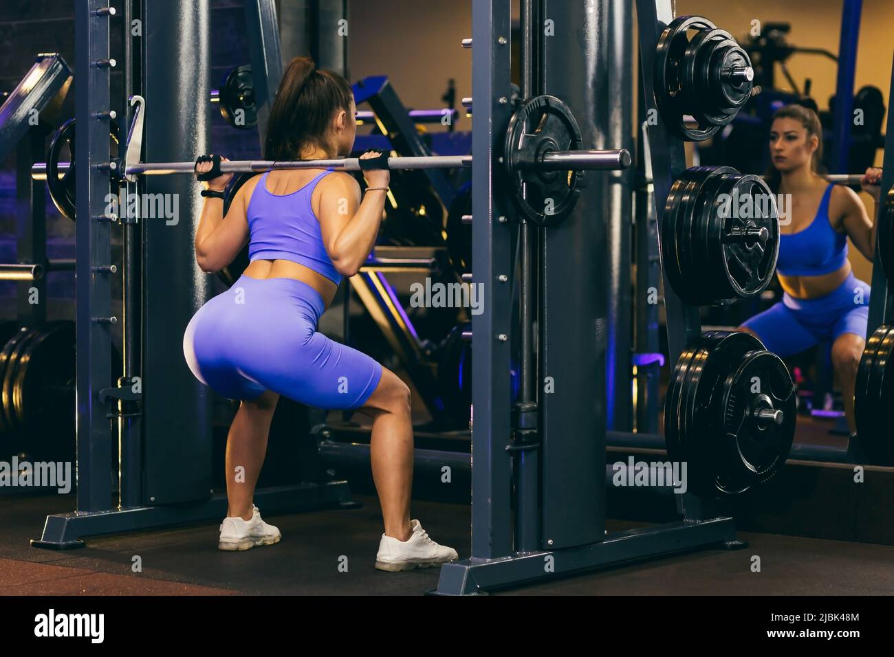 Young beautiful woman, trainer, training in the gym, exercises with ...