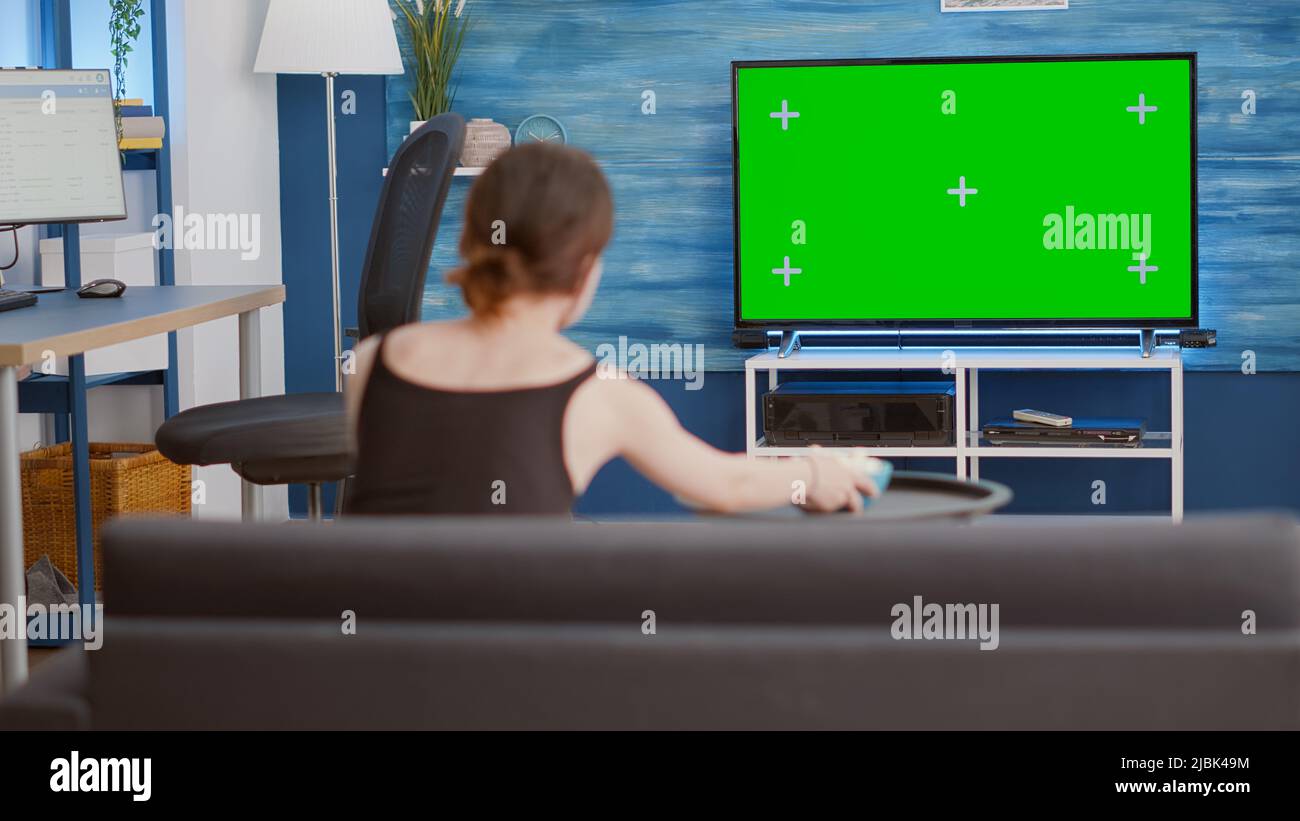 Static tripod shot of young woman watching movie on tv with green ...