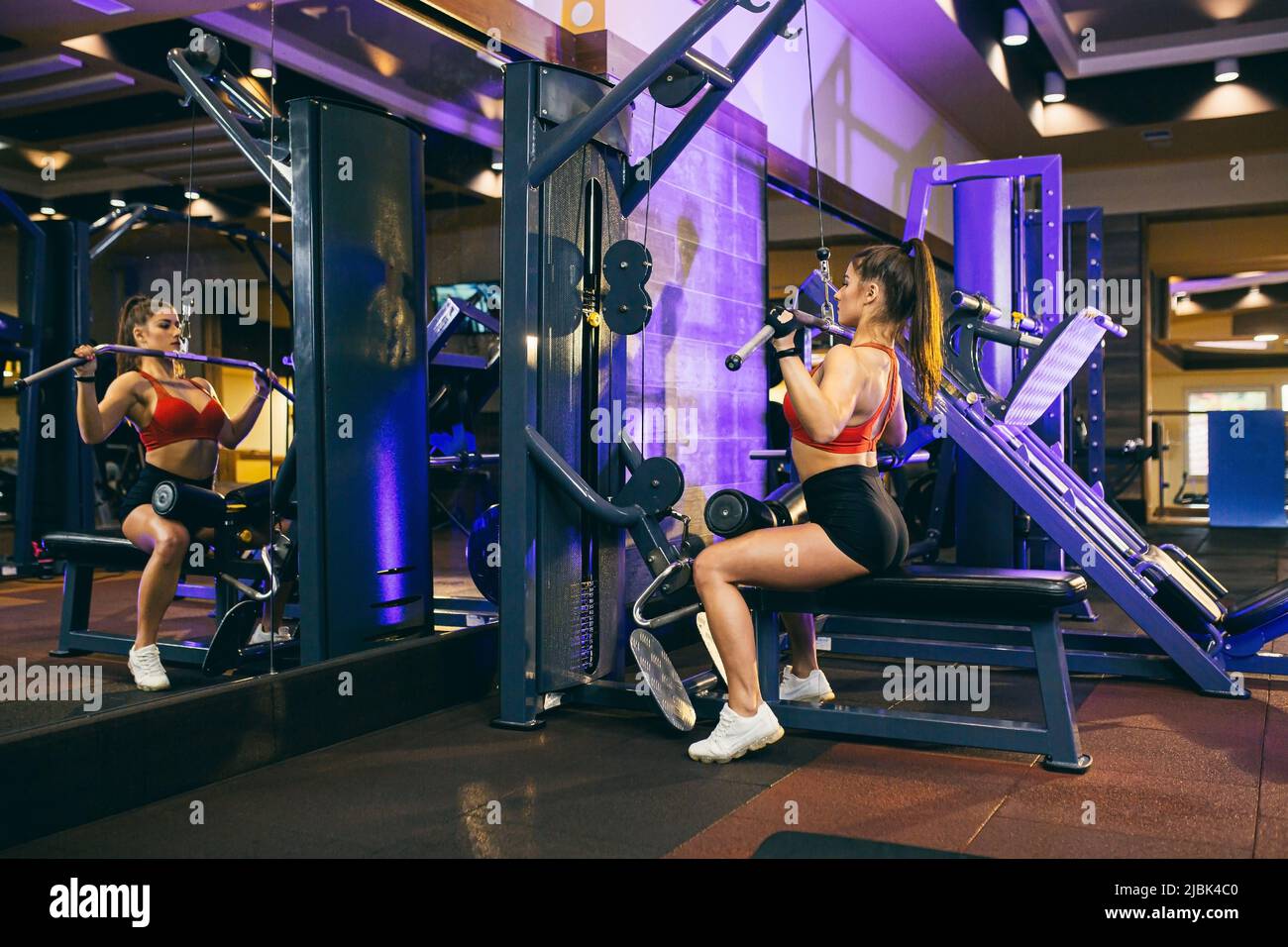 young beautiful sporty woman trains on the simulator, leg exercises ...