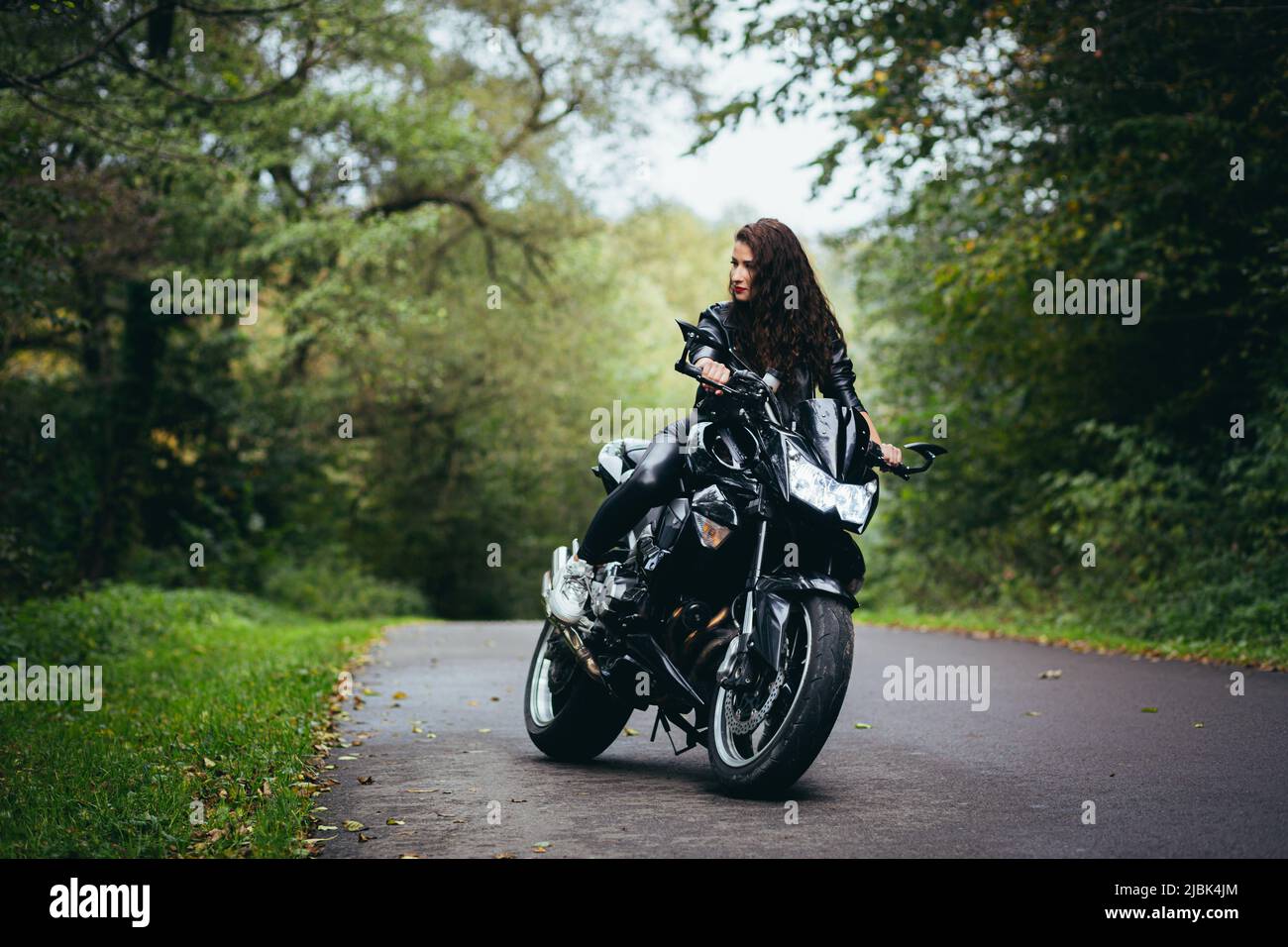 Portrait of a beautiful young woman sitting on a motorcycle, riding a ...
