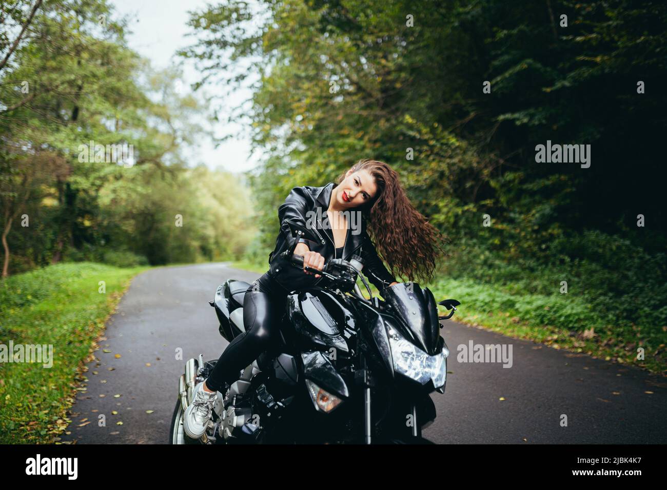 Portrait of a beautiful young woman sitting on a motorcycle, riding a ...