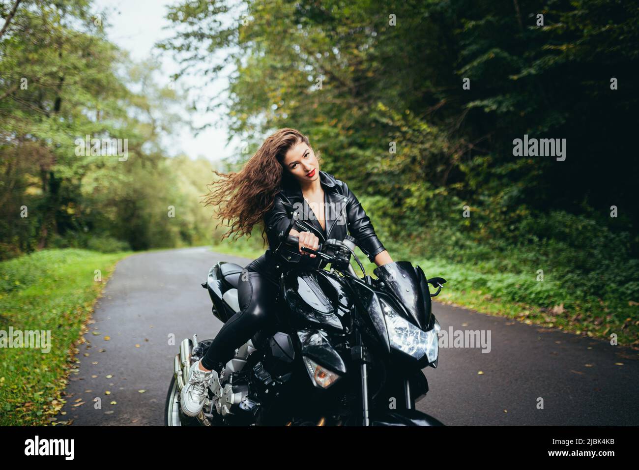 Portrait of a beautiful young woman sitting on a motorcycle, riding a ...