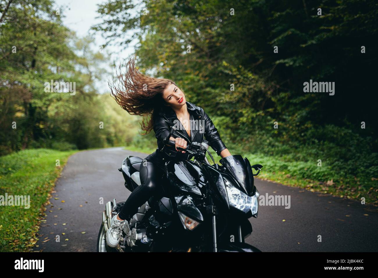 Portrait of a beautiful young woman sitting on a motorcycle, riding a ...