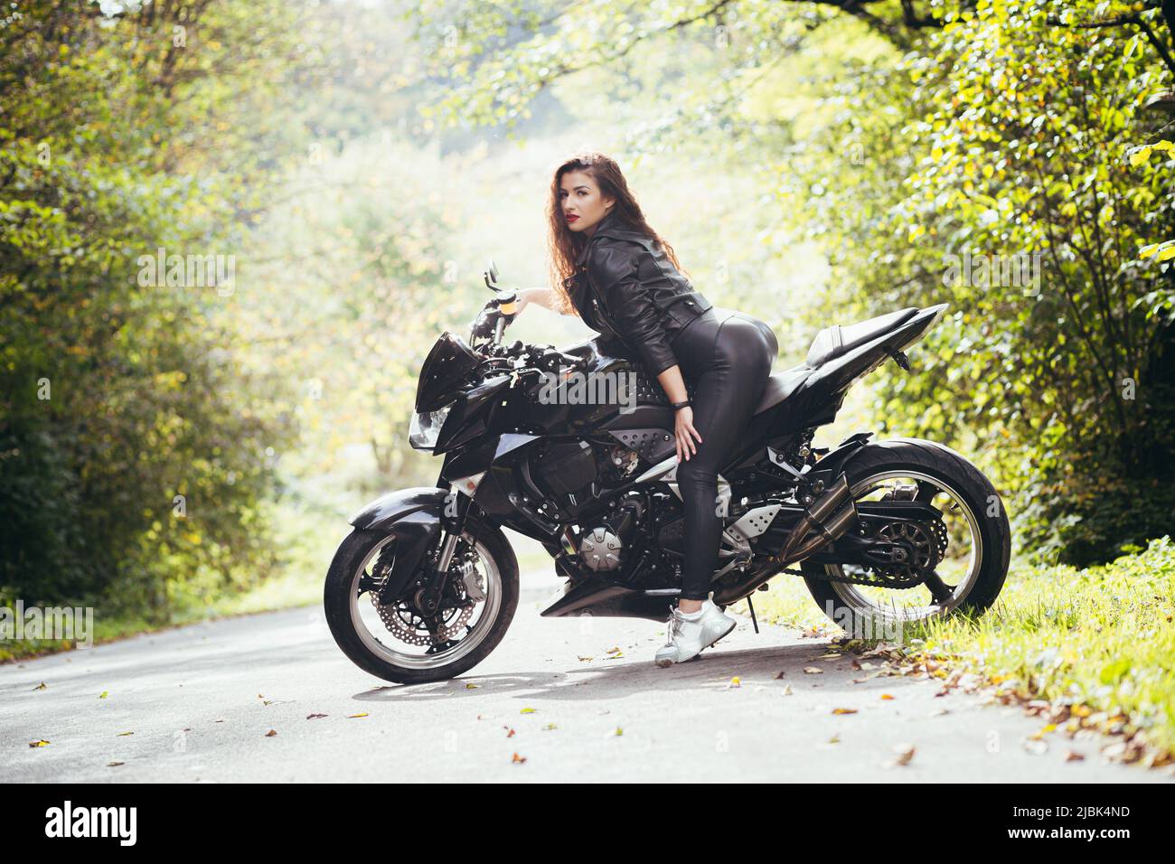 Portrait of a beautiful young woman sitting on a motorcycle, riding a ...
