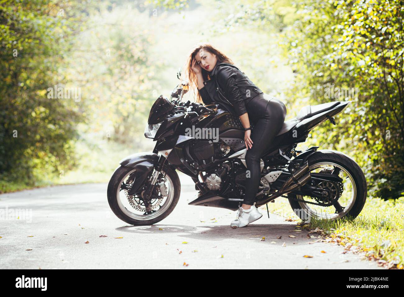 Portrait of a beautiful young woman sitting on a motorcycle, riding a ...