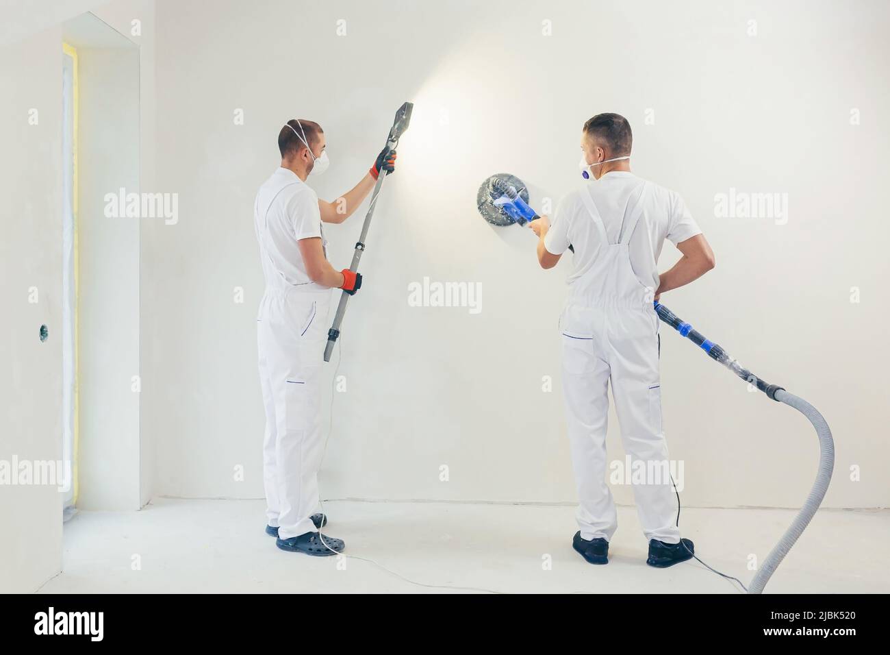Plasterer smoothes the wall surface with a wall grinder. Two master ...