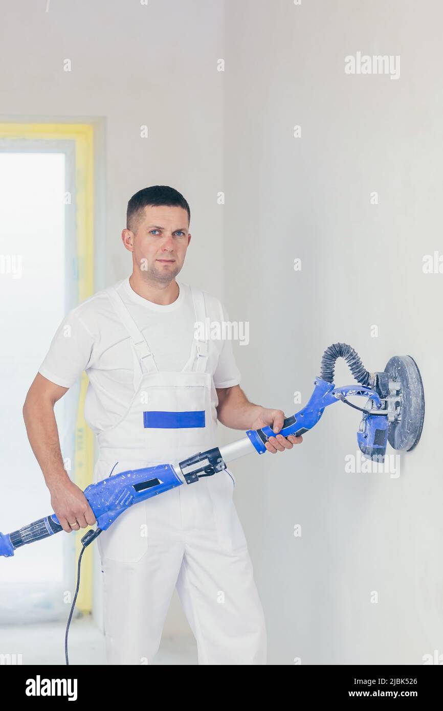 Plasterer smoothes the wall surface with a wall grinder. Two master ...