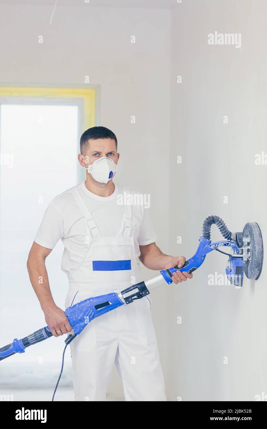 Plasterer smoothes the wall surface with a wall grinder. Two master ...