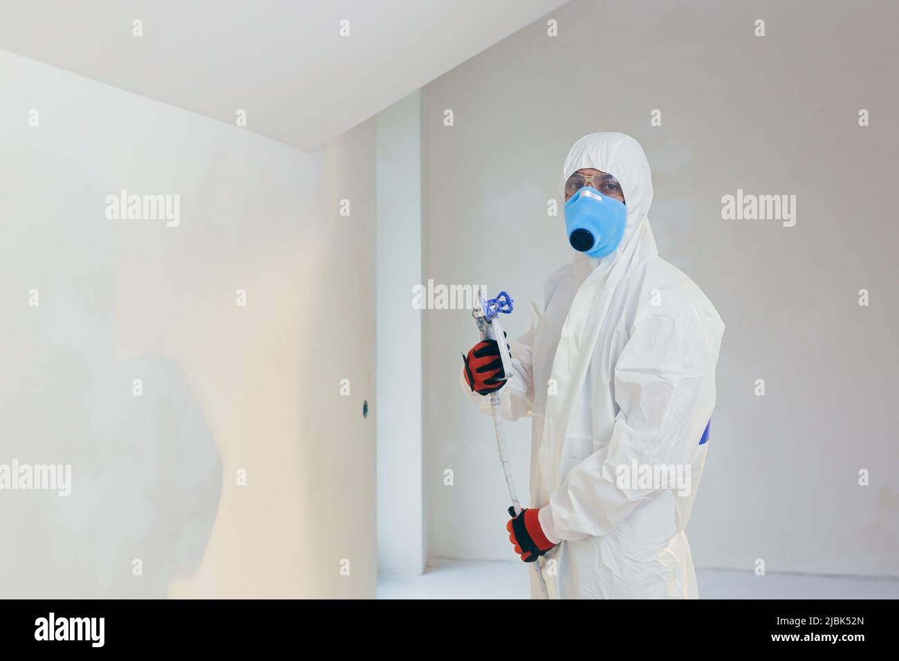 Airless spray paint. The worker paints the wall with an airless spray ...