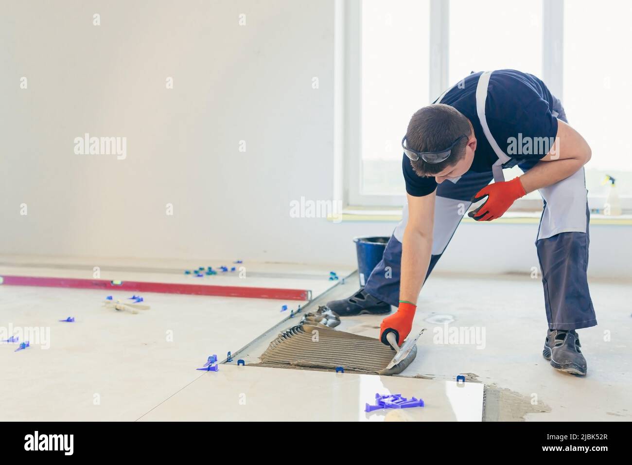 A male construction worker installs a large ceramic tile Stock Photo ...