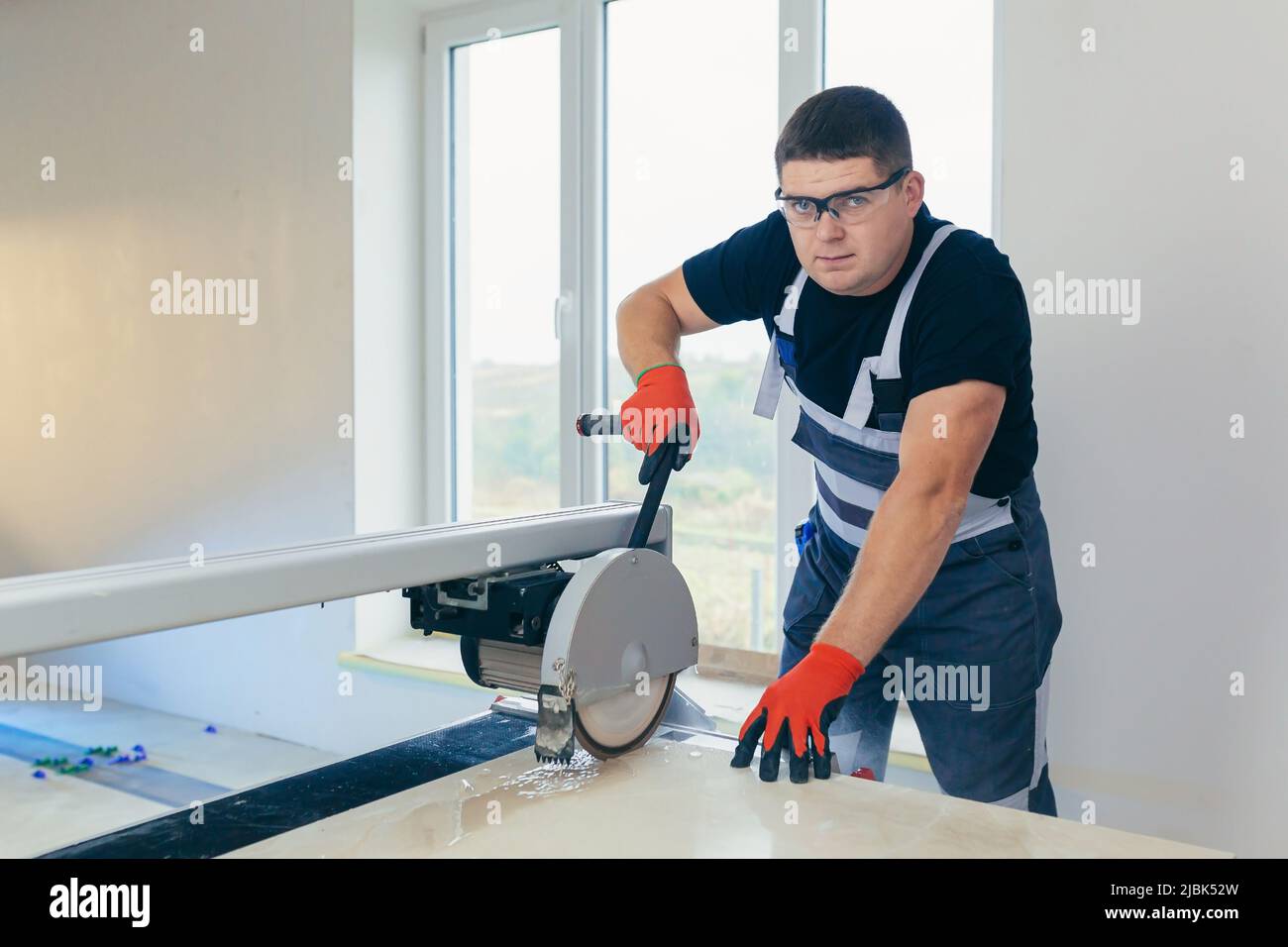 Master man, builder cuts a tile. Machine with a circular saw Stock ...