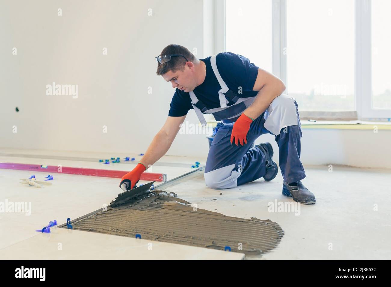 A male construction worker installs a large ceramic tile Stock Photo ...