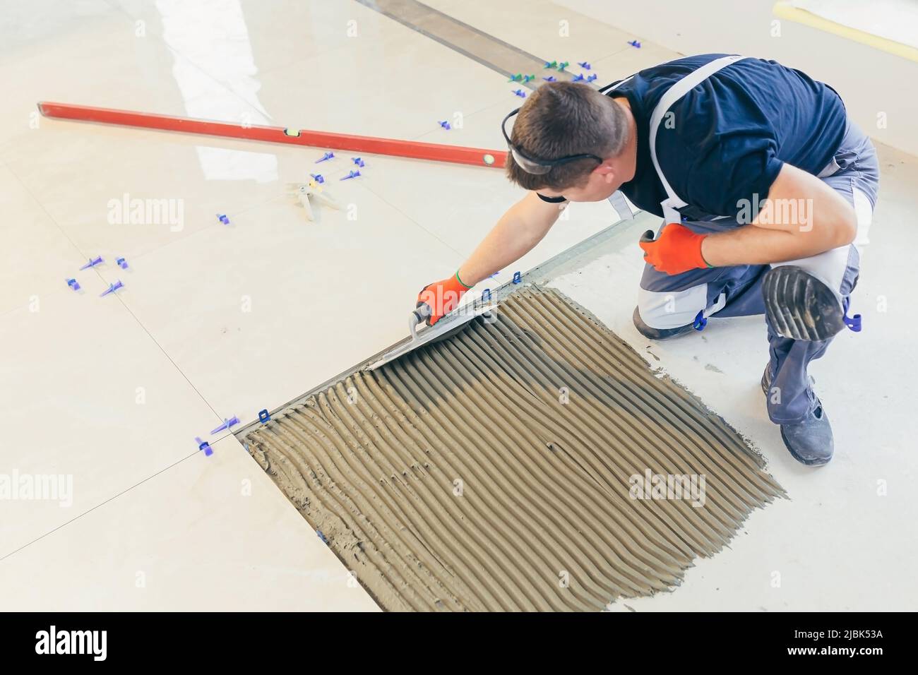 A male construction worker installs a large ceramic tile Stock Photo ...