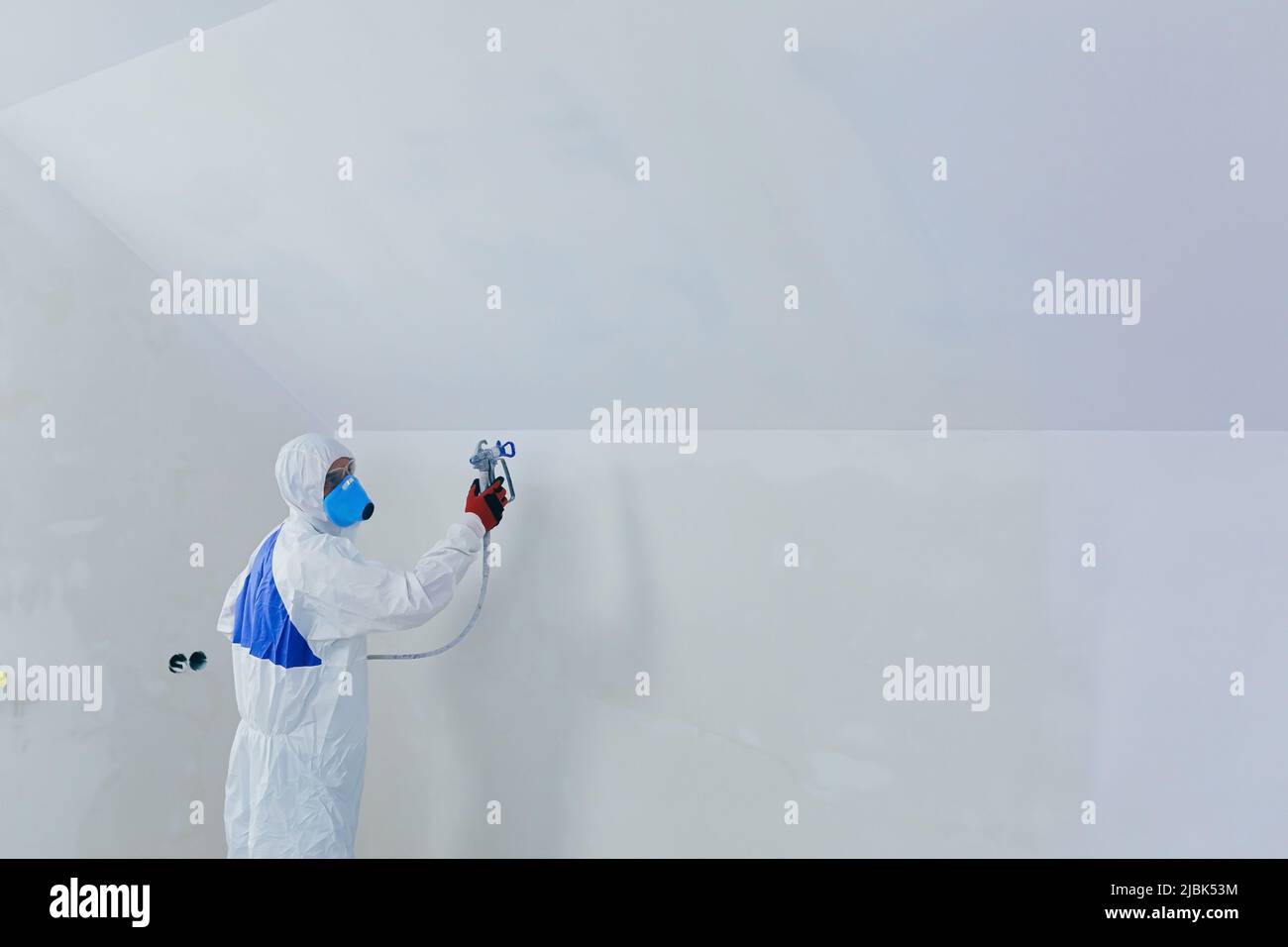 Airless spray paint. The worker paints the wall with an airless spray ...