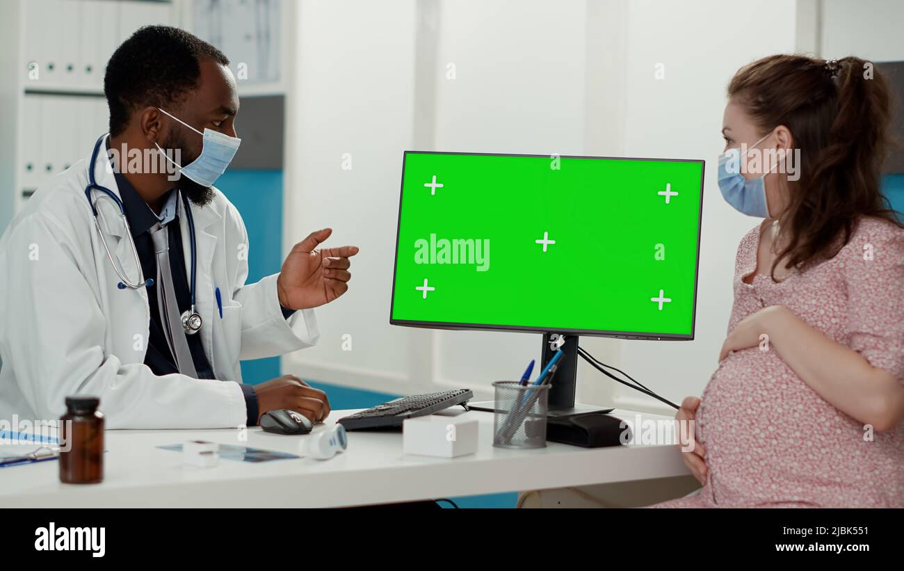People with face mask using computer with greenscreen at pregnancy ...