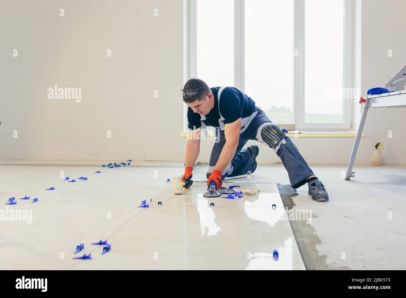 A male construction worker installs a large ceramic tile Stock Photo ...