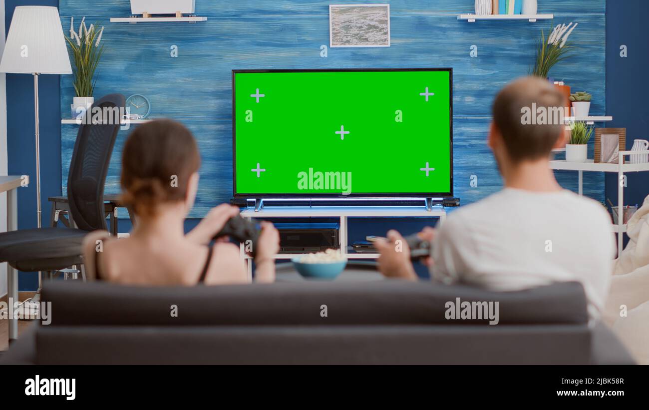 Back view of young woman and boyfriend gamers holding controllers ...