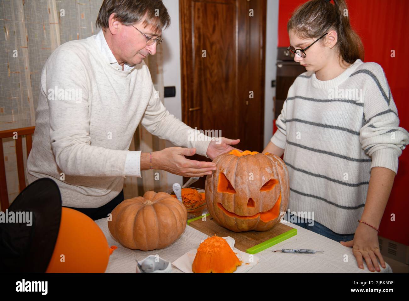 Father And Daughter Carving Pumpkin Jack O Lanterns On Halloween At