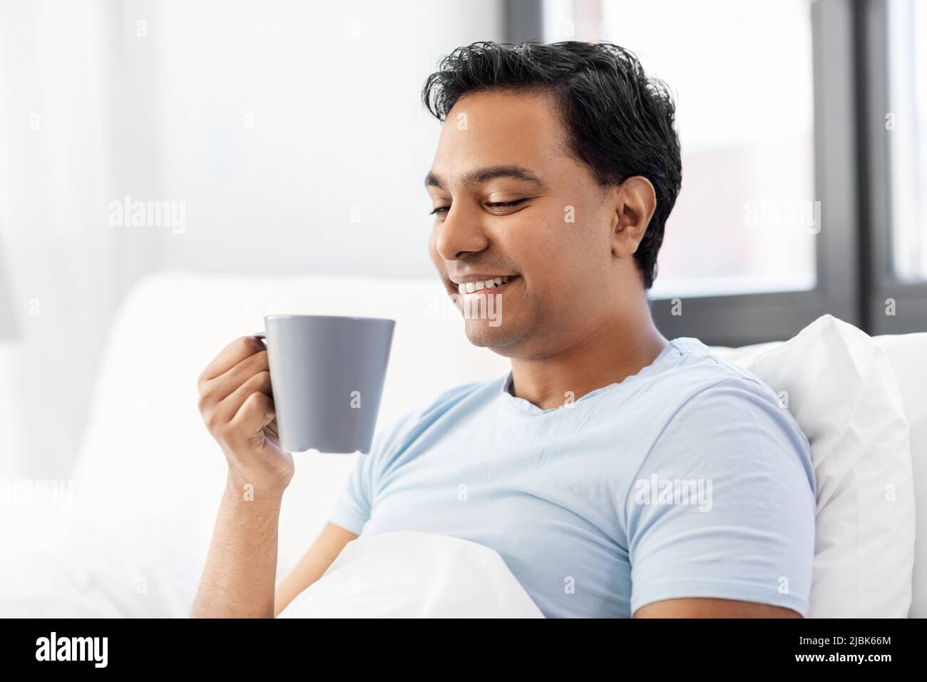 happy indian man drinking coffee in bed at home Stock Photo - Alamy