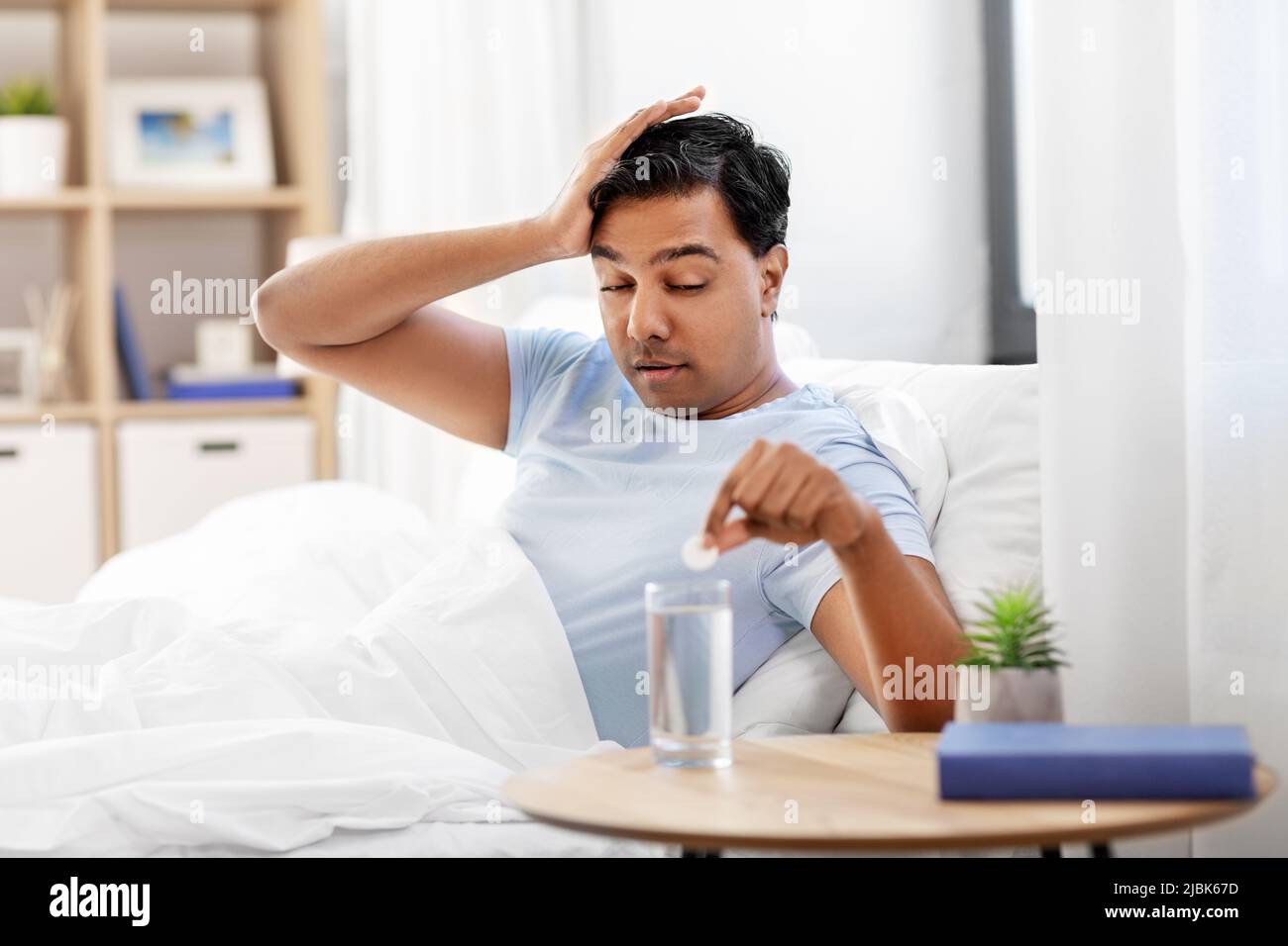sick man in bed with medicine and glass of water Stock Photo - Alamy