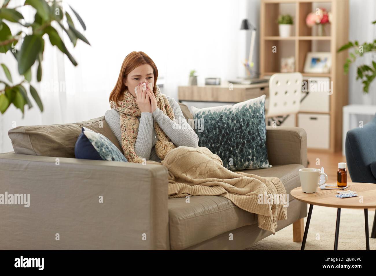 sick woman blowing nose in paper tissue at home Stock Photo - Alamy