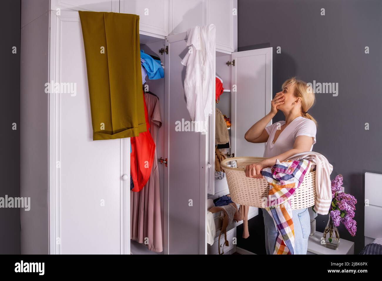 a woman stands in front of a closet with clothes. Emotion - surprise ...