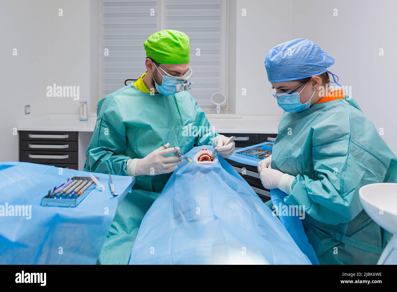 Dentist surgeon and assistant perform surgery and treatment of the ...