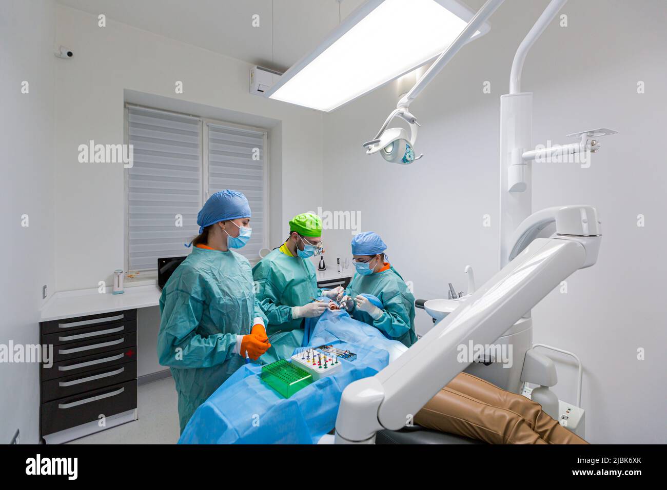 Dentist surgeon and assistant perform surgery and treatment of the ...