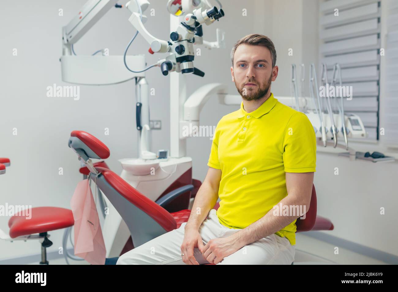 Portrait of a young dentist, assistant in a yellow medical uniform ...