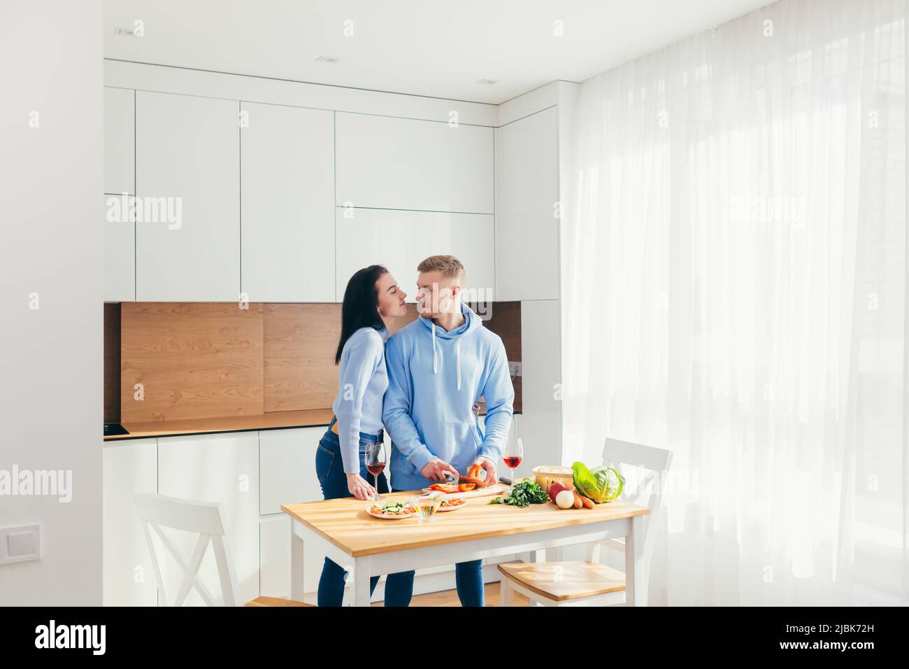 Young beautiful couple, man and woman cook together in the kitchen at ...