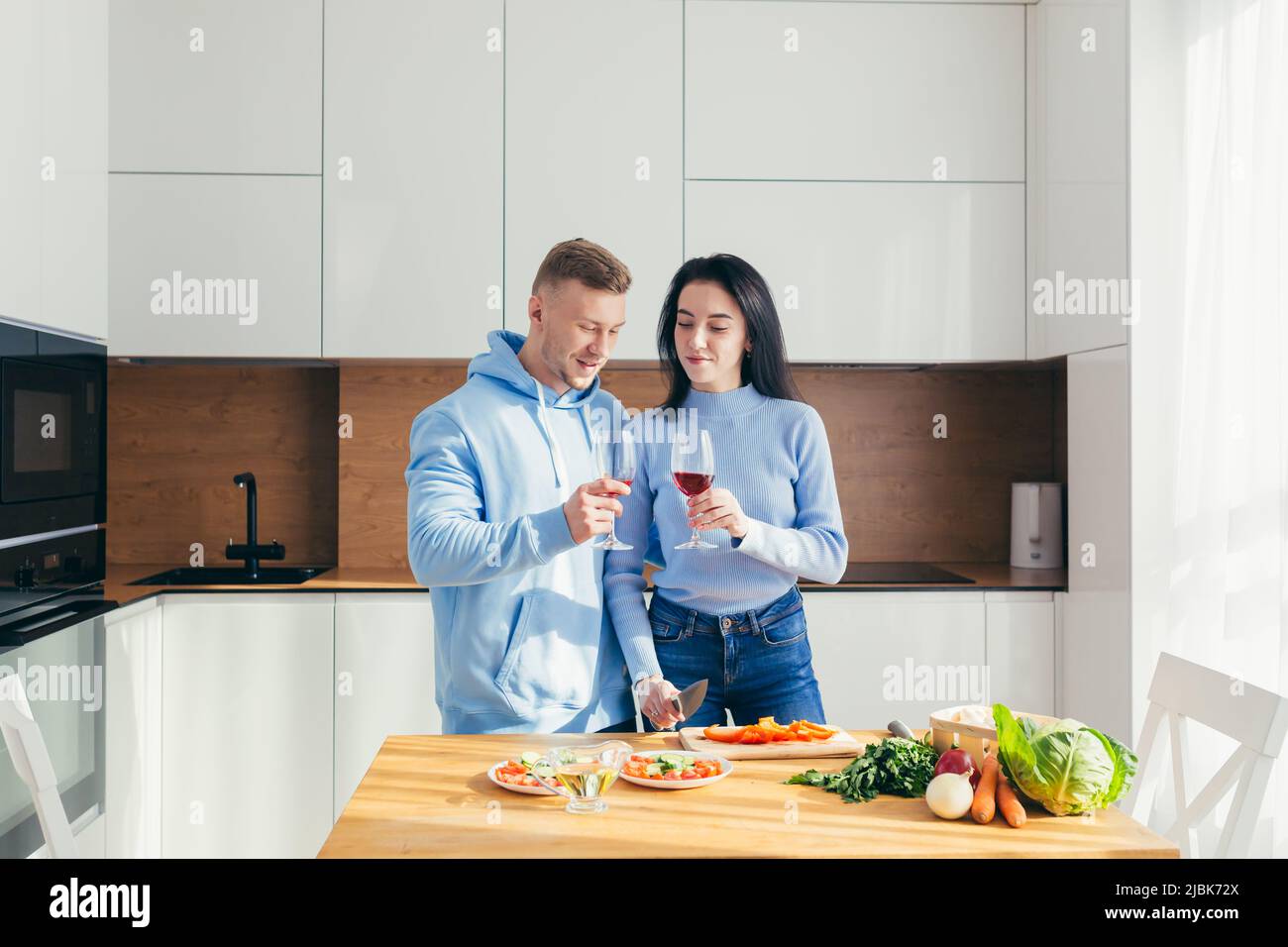 Young beautiful couple, man and woman cook together in the kitchen at ...