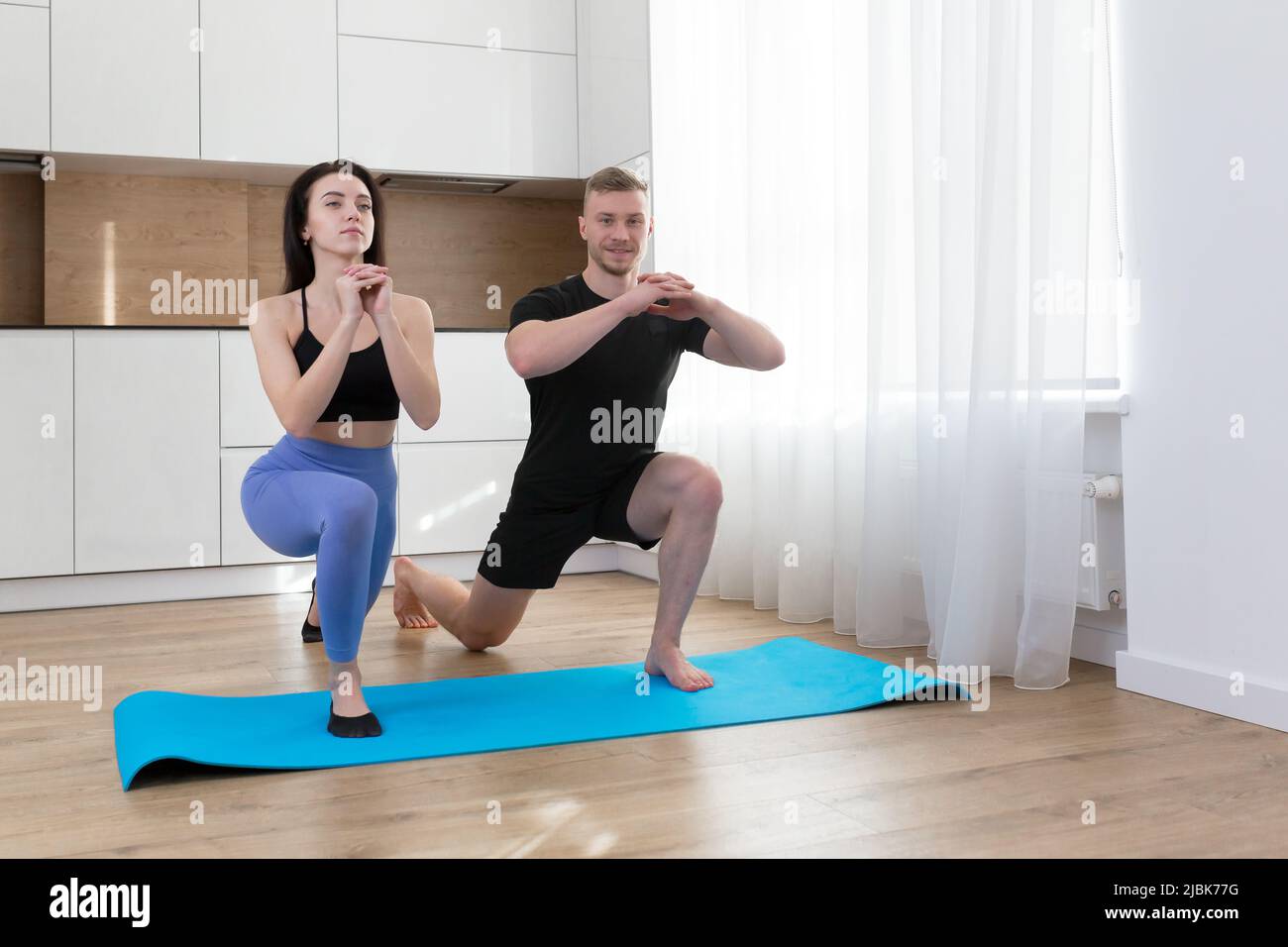 A young couple, a man and a woman play sports together at home on the ...