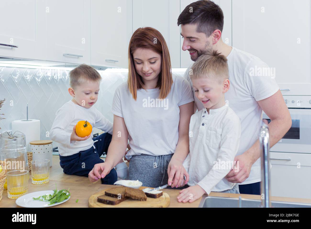 Young family, mom, dad, two children, boys cook breakfast, sandwiches ...