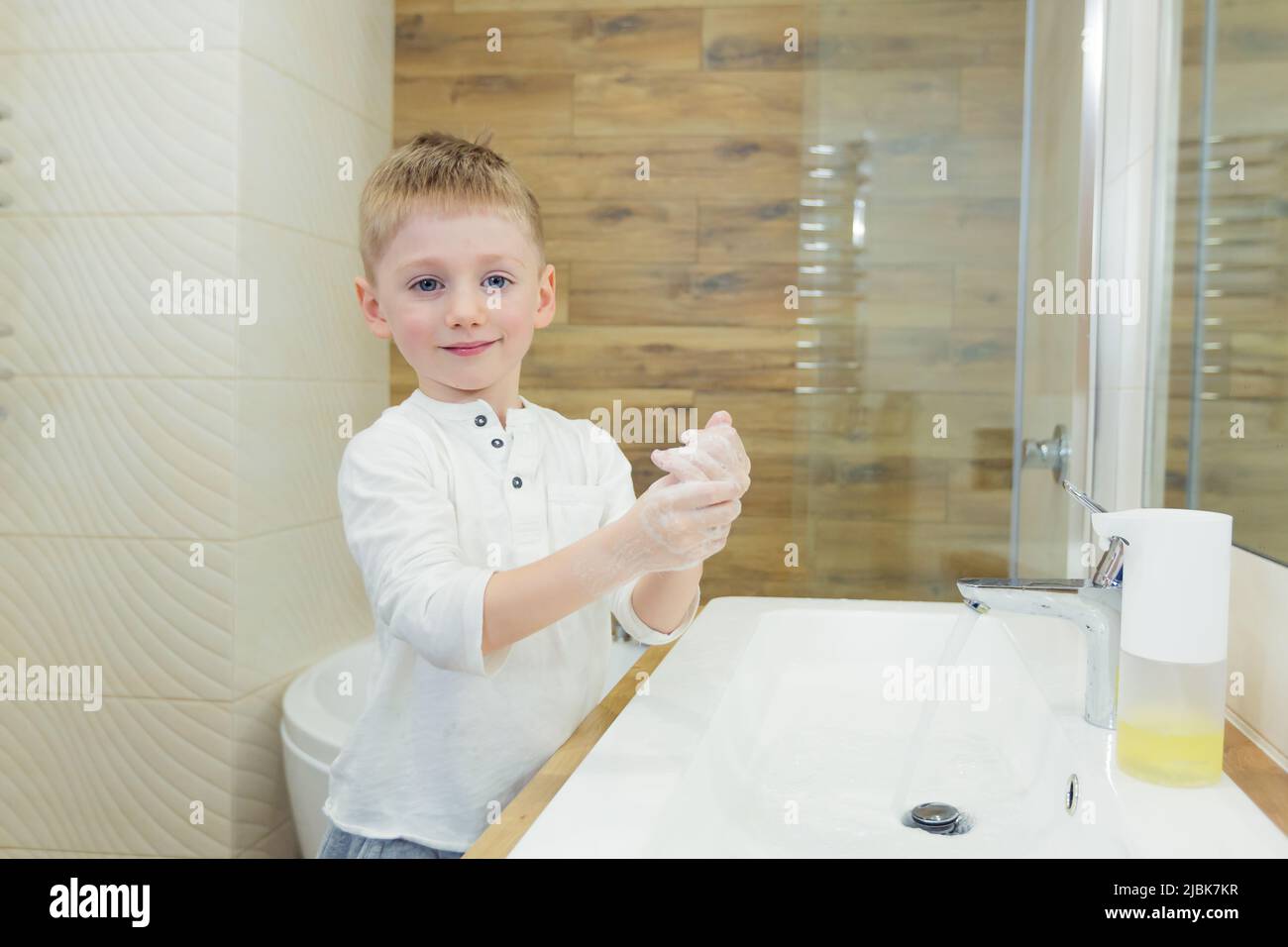 Little boy washes his hands with soap, disinfects in the bathroom, at ...