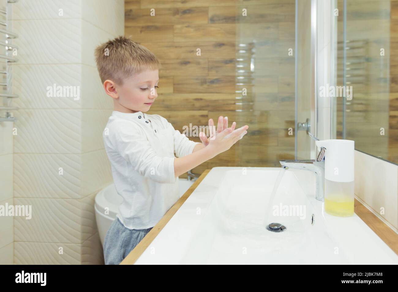 Little boy washes his hands with soap, disinfects in the bathroom, at ...