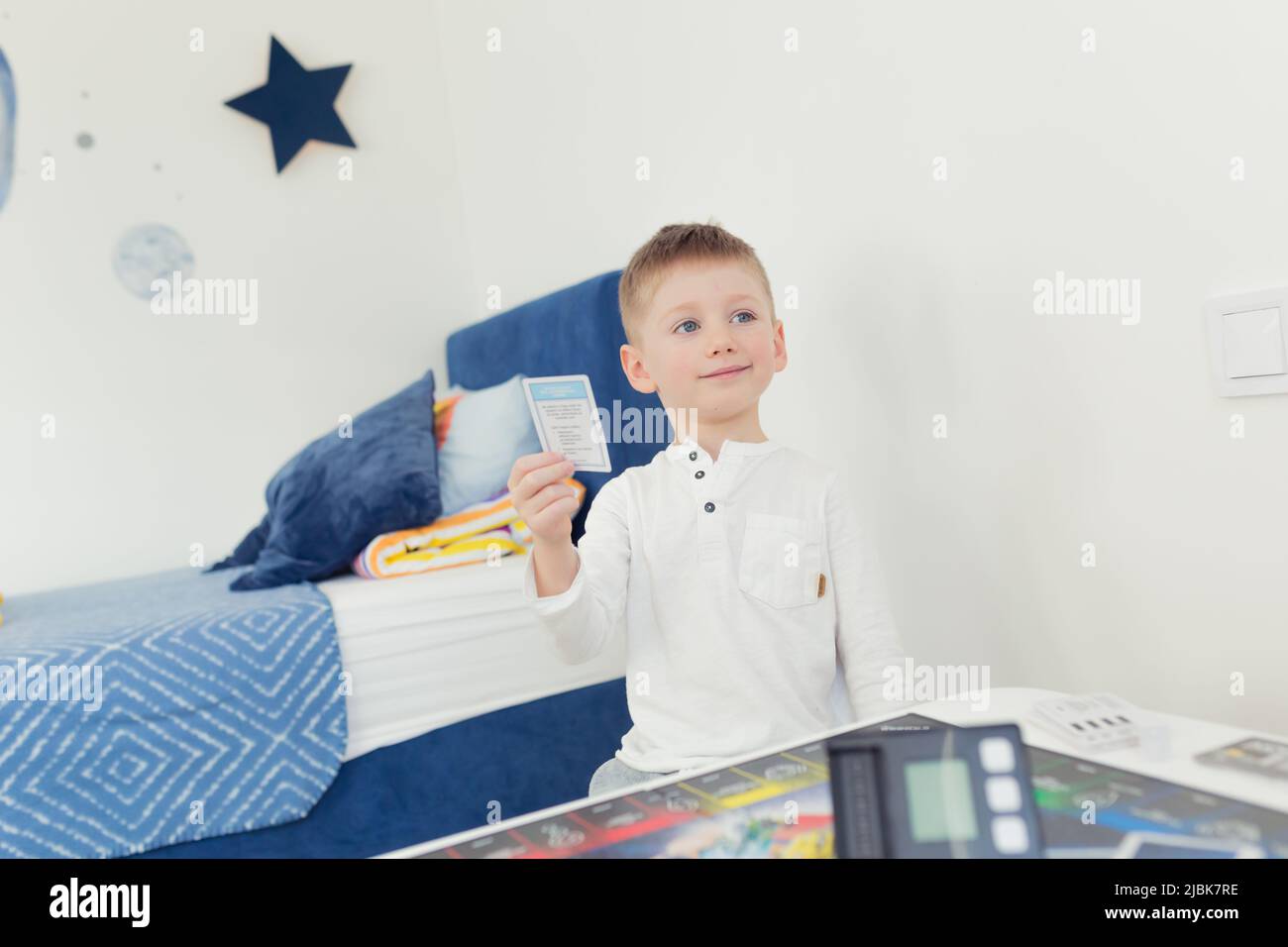 Little boy playing board game at the table in the nursery, smiling ...