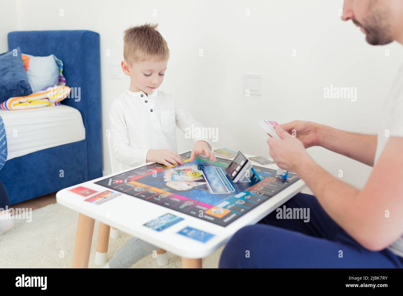 Family, father and son play a board game together at the table in the ...