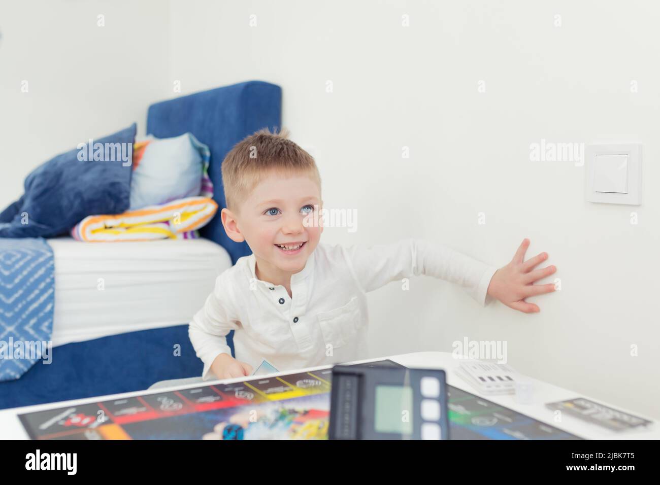 Little boy playing board game at the table in the nursery, smiling ...