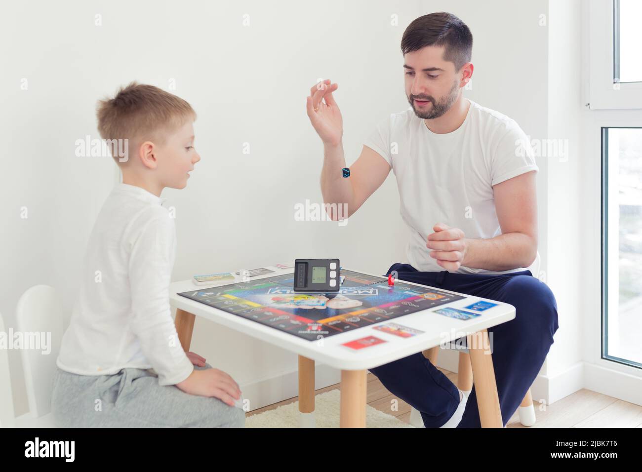 Family, father and son play a board game together at the table in the ...