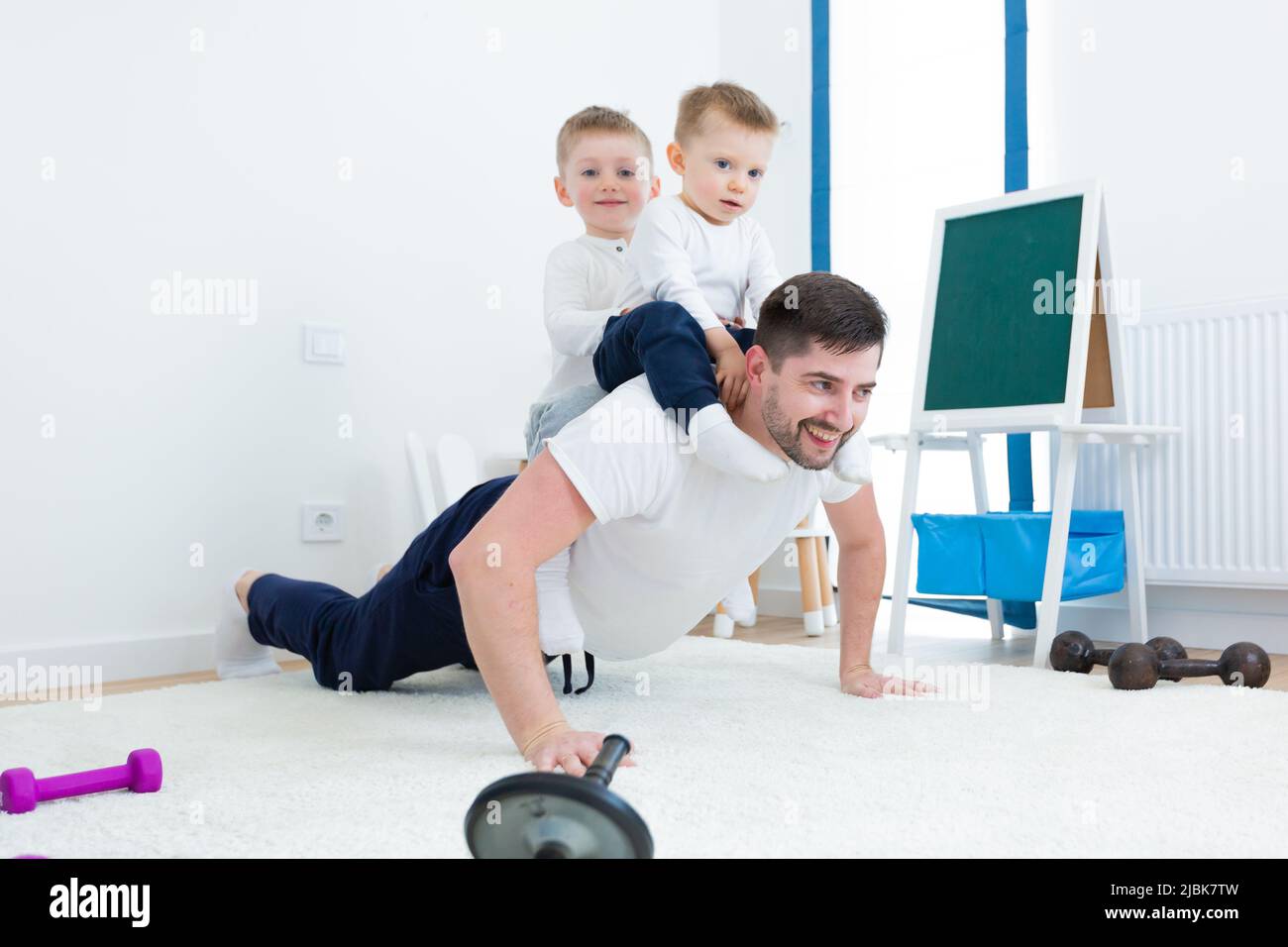Young father and two children, two sons go in for sports, do push-ups ...