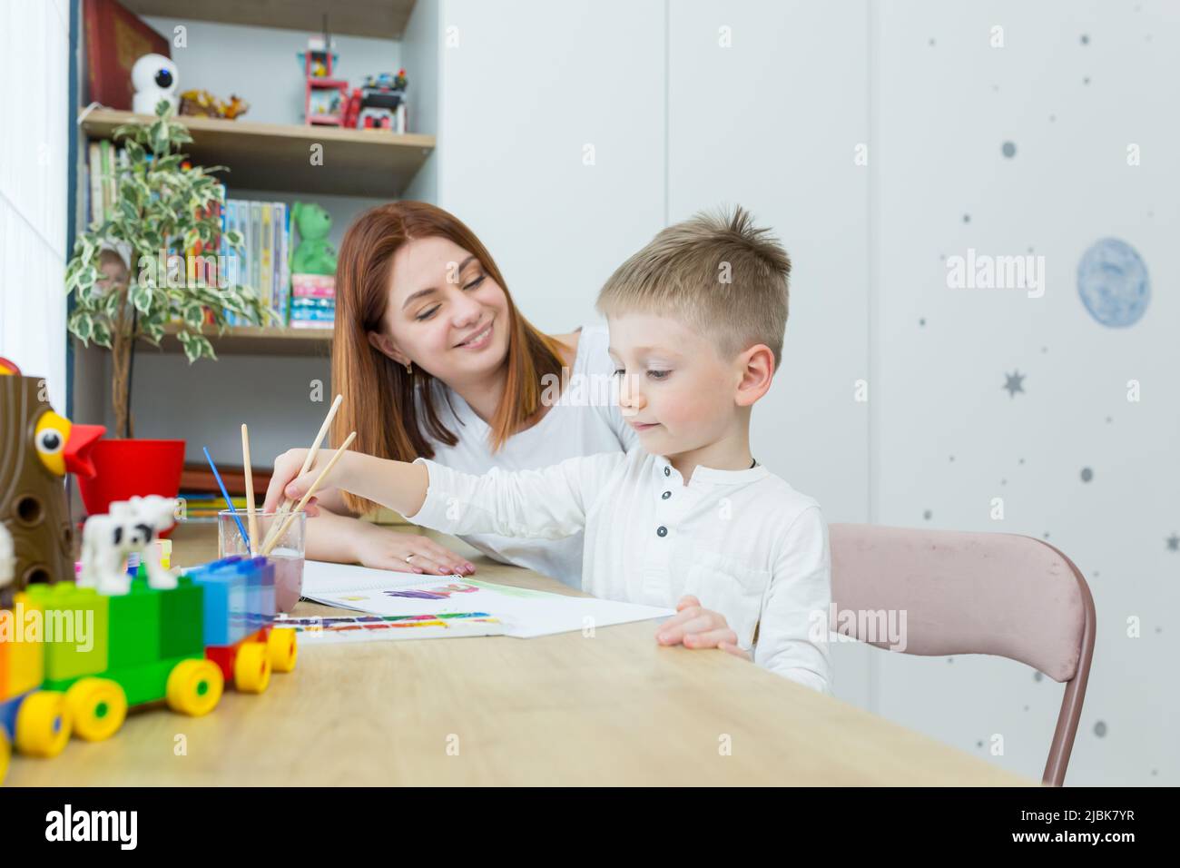 Young mother and son study at home in quarantine, paint at the table, have fun together. Smile ...