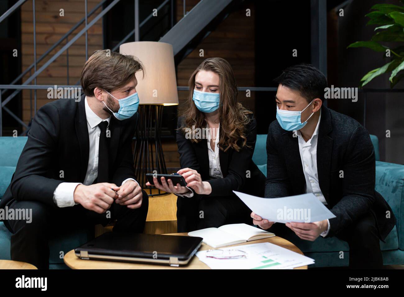 Group of men and woman hold business meeting, near laptop, wearing ...
